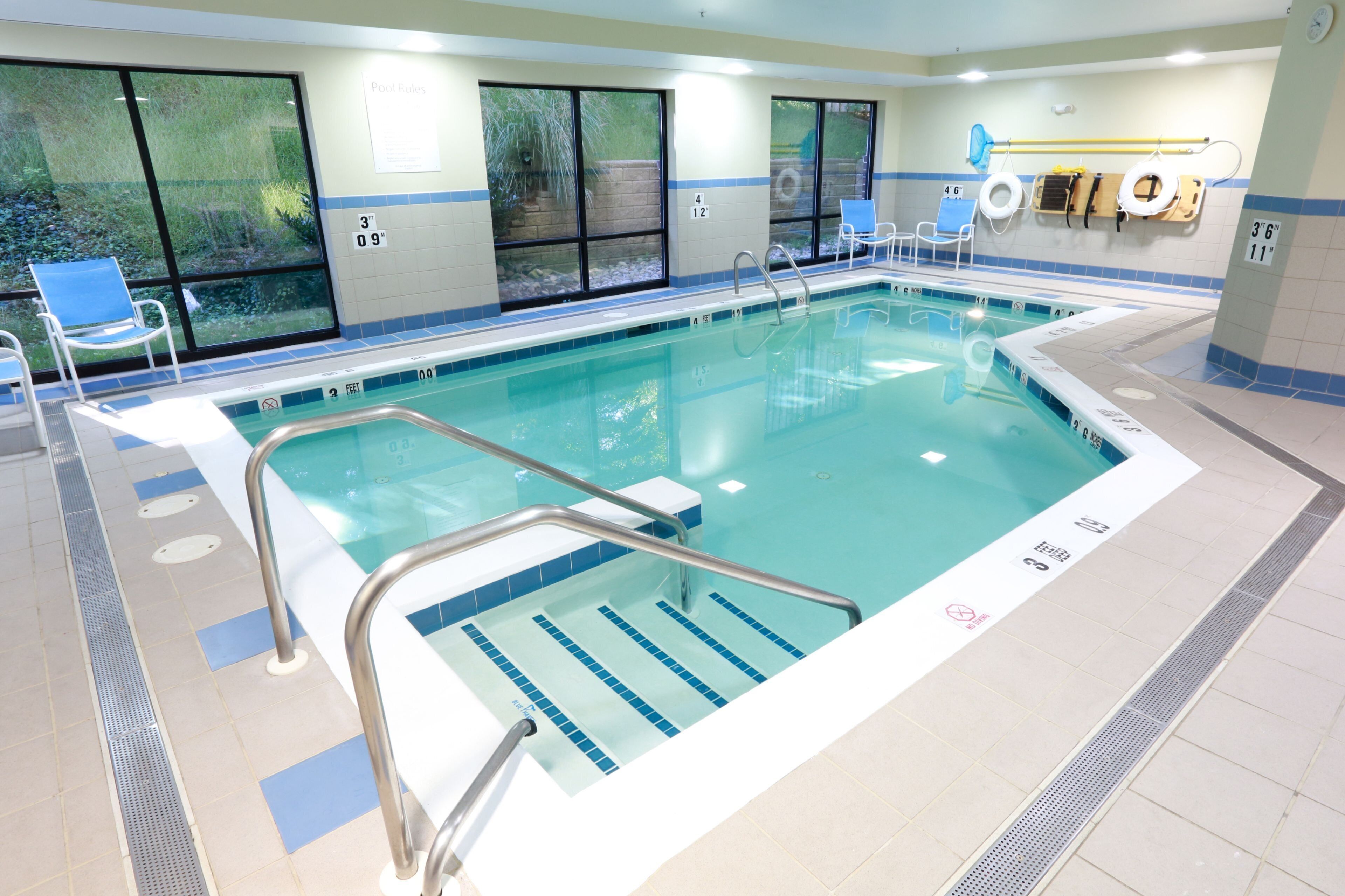 Piscina interior com faixas de separação bem visíveis, uma escada de segurança e placa indicando que mergulhos não são permitidos.