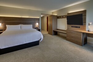 Quarto de hotel moderno com uma cama grande, uma escrivaninha com TV de tela plana e um guarda-roupa.