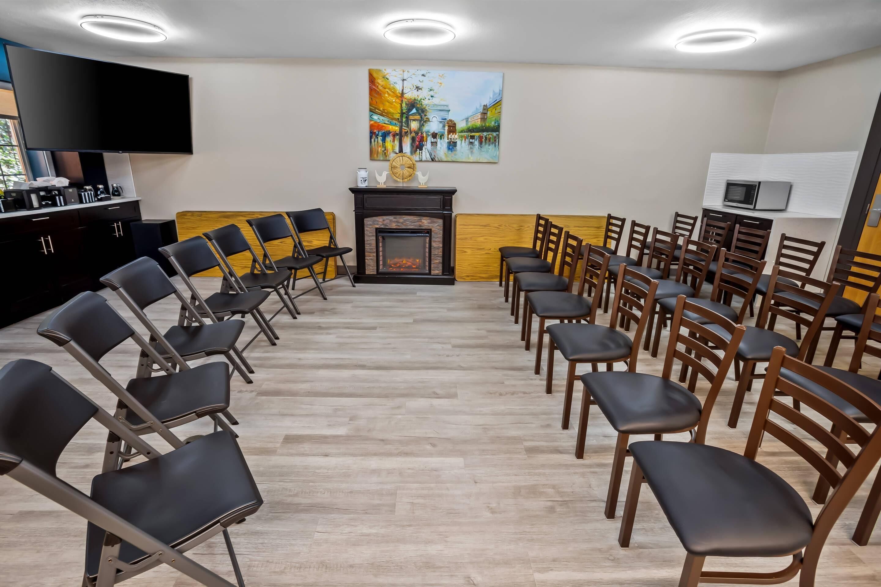 Uma sala de conferências com lareira, uma TV de tela plana e um quadro na parede.