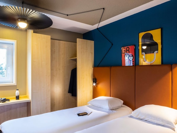 Quarto de hotel com cama, mesa de cabeceira, espelho e janela.