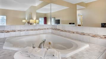 Uma casa de banho moderna com uma banheira grande, um lavatório com espelho e uma janela que permite a entrada de luz natural.