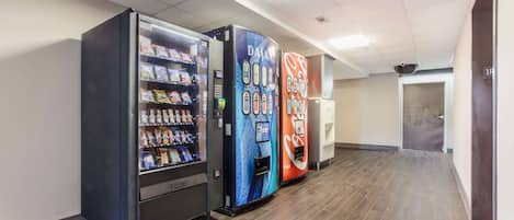 Corredor com máquinas de venda automática e uma porta no final.