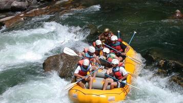 Um grupo de pessoas fazendo rafting em um rio, cercado por pedras e grandes rochas.