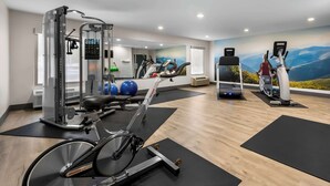 Uma academia moderna com máquinas de cardio, equipamentos de musculação e bolas de exercício.