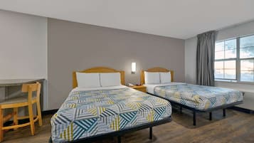 Quarto com duas camas de solteiro, uma escrivaninha e uma cadeira.