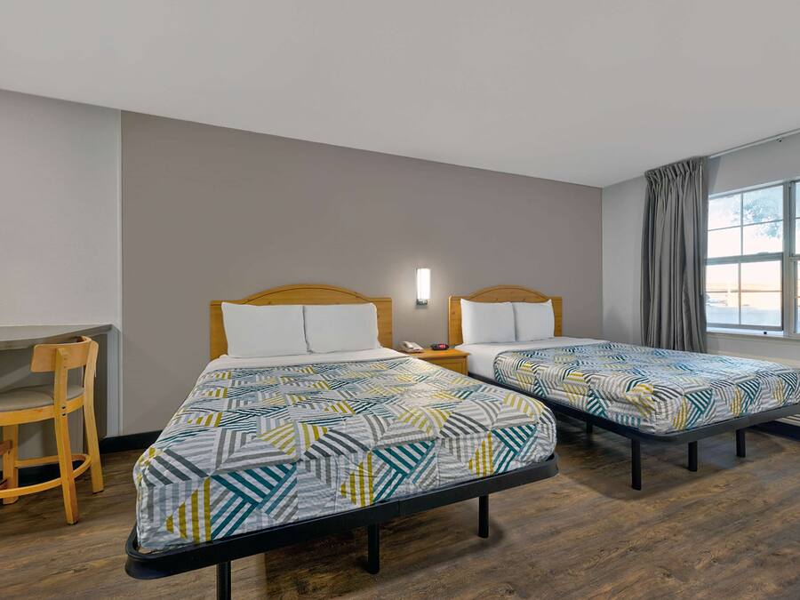 Quarto com duas camas de solteiro, uma escrivaninha e uma cadeira.