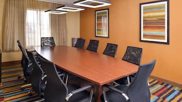 Uma sala de conferência com uma mesa comprida, cadeiras pretas e obras de arte emolduradas nas paredes.