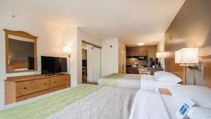 Quarto de hotel com duas camas, televisão, cómoda e uma kitchenette.