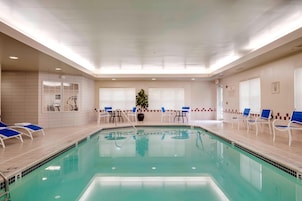 Piscina com espreguiçadeiras e uma pequena mesa no centro.