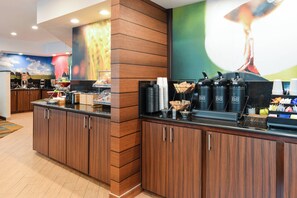 Uma área de recepção de hotel com armários de madeira, um espaço para café e um mural na parede.