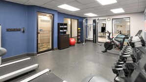 Uma academia com equipamentos de ginástica, incluindo esteiras, bicicleta ergométrica e pesos livres.