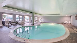 Piscina interna com água cristalina, rodeada por espreguiçadeiras e piso revestido.