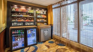 Um saguão de hotel com máquinas de venda automática, um mini-frigorífico e um pequeno frigorífico.