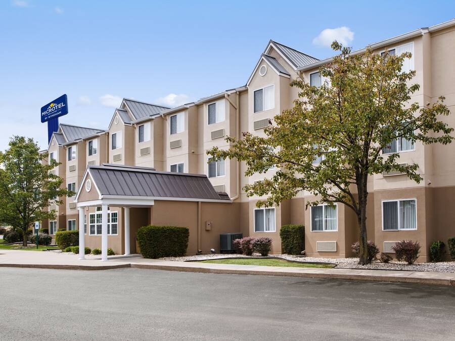 Um Microtel Inn com fachada bege, várias janelas e entrada coberta.