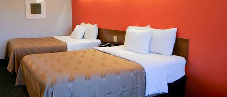 Quarto de hotel com duas camas, cada uma com lençóis brancos e colcha estampada.