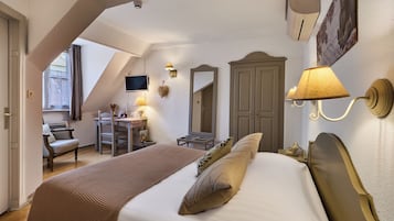 Quarto de hotel com cama, escrivaninha, cadeira, televisão e guarda-roupa.