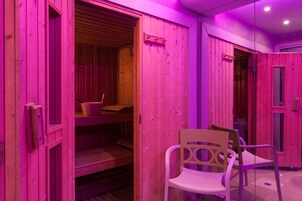 Uma cabana de madeira com sauna, bancos de madeira e cadeiras brancas.