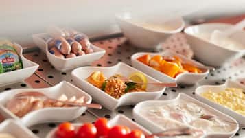 Buffet com diversos pratos, incluindo salsichas, saladas e patês.