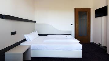 Quarto de hotel com cama, mesa de cabeceira e porta.