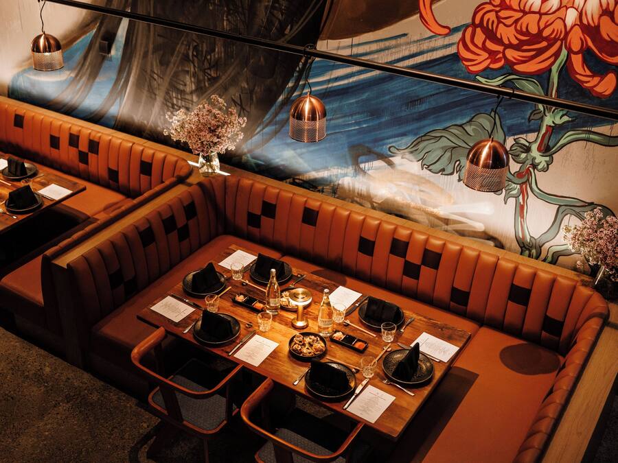 Restaurante com assentos em camarote, mesas preparadas para refeições e luminárias pendentes.