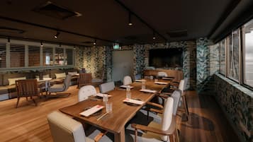 Uma sala de conferências com uma mesa comprida, cadeiras e uma televisão.