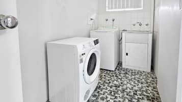 Uma lavanderia compacta com máquina de lavar, pia e armário.