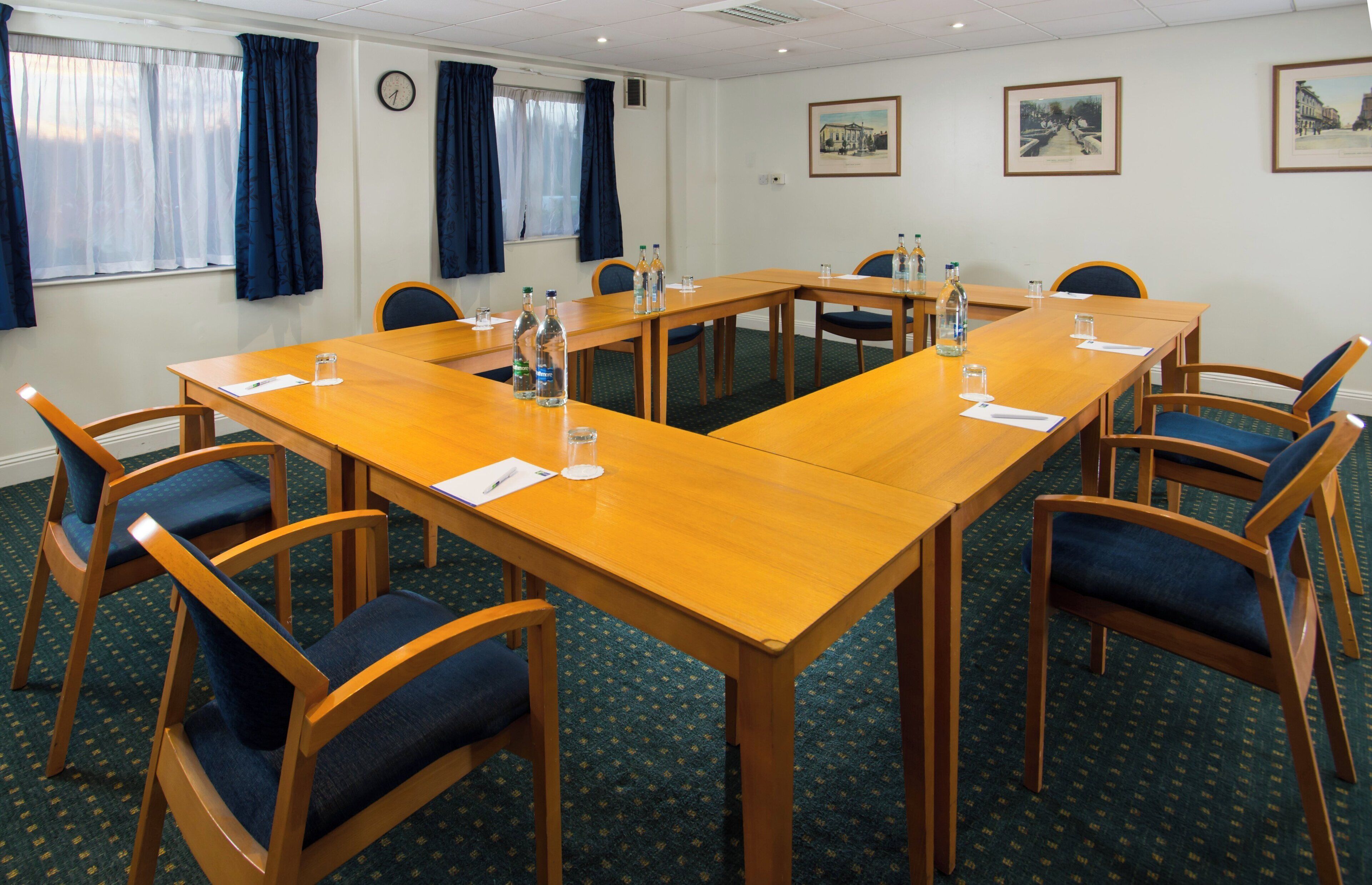 Uma sala de conferências com uma mesa comprida, cadeiras e um relógio na parede.