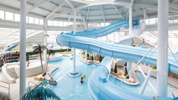 Um grande parque aquático coberto com muitos toboáguas e piscinas.
