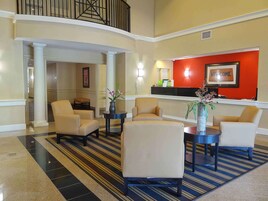 Um hall com uma mesa de recepção, dois sofás, uma mesa de centro e um tapete listrado.