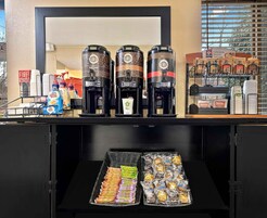 Um espaço com estação de café, duas máquinas de café, um tabuleiro de pastelaria e uma seleção de cápsulas de café.