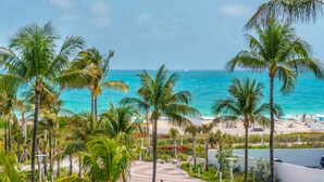 Um resort tropical na praia com palmeiras, um caminho que leva à praia e vista para o oceano.
