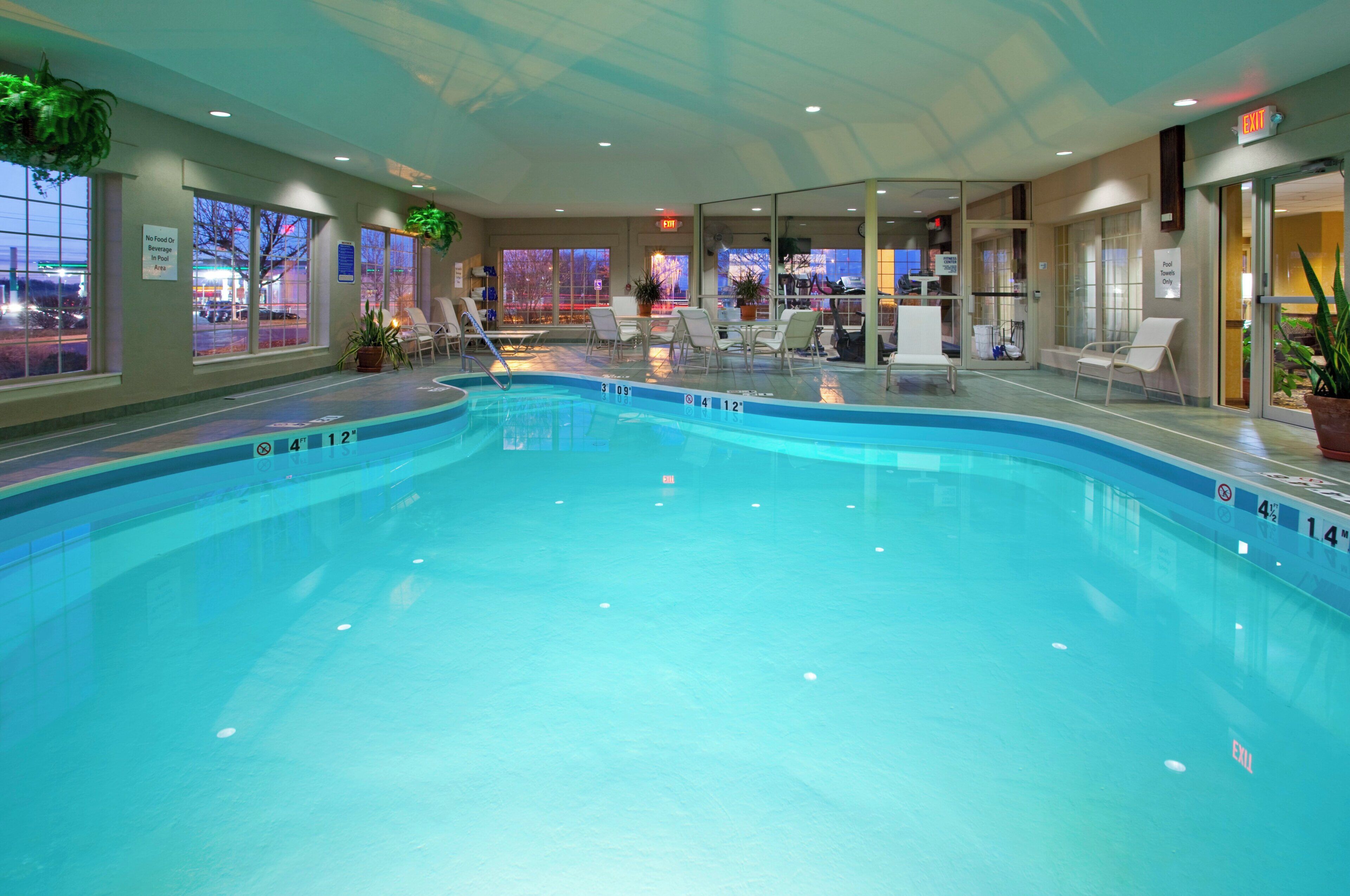 Piscina interior com água cristalina, linhas de profundidade demarcadas e espreguiçadeiras ao redor.