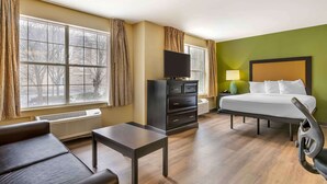 Quarto de hotel com cama, escrivaninha, cadeira, televisão e aquecedor.
