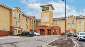 Hotel com hall central amplo, vários espaços de estacionamento e céu azul límpido.