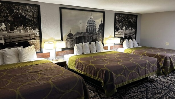 Quarto de hotel com duas camas, uma moldura grande com uma imagem de um edifício e um tapete estampado.
