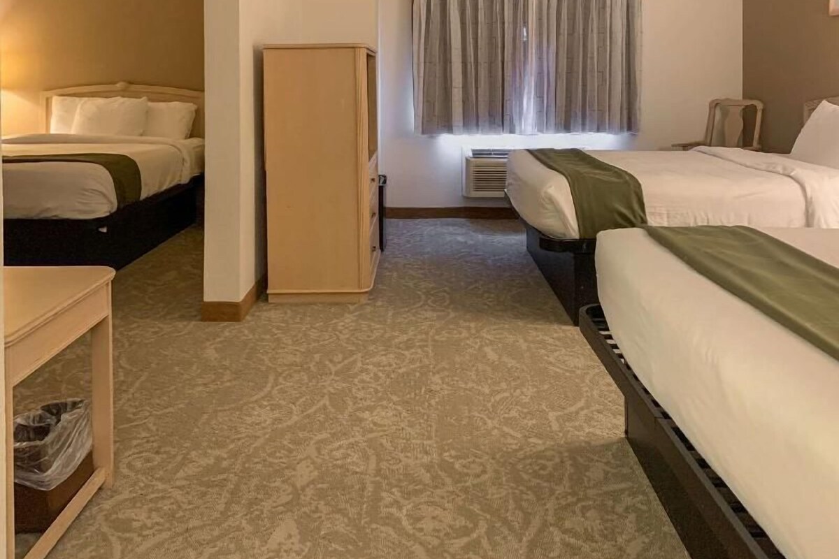 Quarto de hotel com duas camas, um guarda-roupa e uma janela com cortinas.