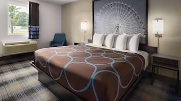 Quarto de hotel com uma cama grande, uma poltrona, uma luminária fixada na parede e uma grande decoração na parede.
