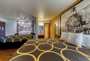 Quarto de hotel com duas camas, uma grande pintura de um trem e vista para as montanhas.