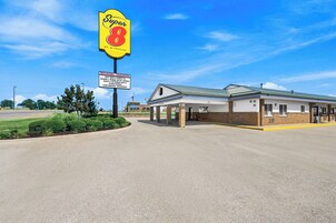 Um motel Super 8 com céu claro, um letreiro convidativo para caminhoneiros e uma estrutura de edifício simples.