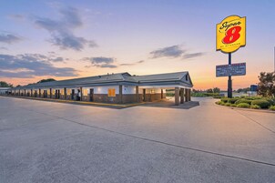Um motel Super 8, com um edifício de um andar, estacionamento e um grande letreiro anunciando o motel.