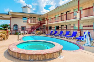 Um hotel com piscina, várias varandas e espreguiçadeiras.