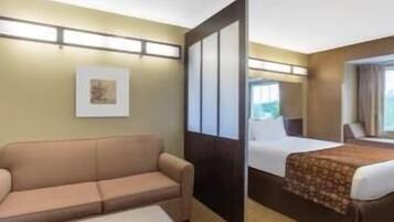 Quarto de hotel com cama, sofá e mesa pequena.