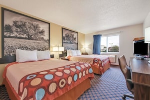 Quarto de hotel com duas camas, uma escrivaninha, uma cadeira e uma televisão.