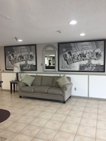 Sala de estar com sofá cinzento, duas imagens emolduradas do Texas, um espelho e uma mesinha com abajur.