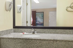 Casa de banho com bancada de granito, lavatório e espelho.