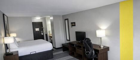 Quarto de hotel com cama, escrivaninha, cadeira e duas luminárias.