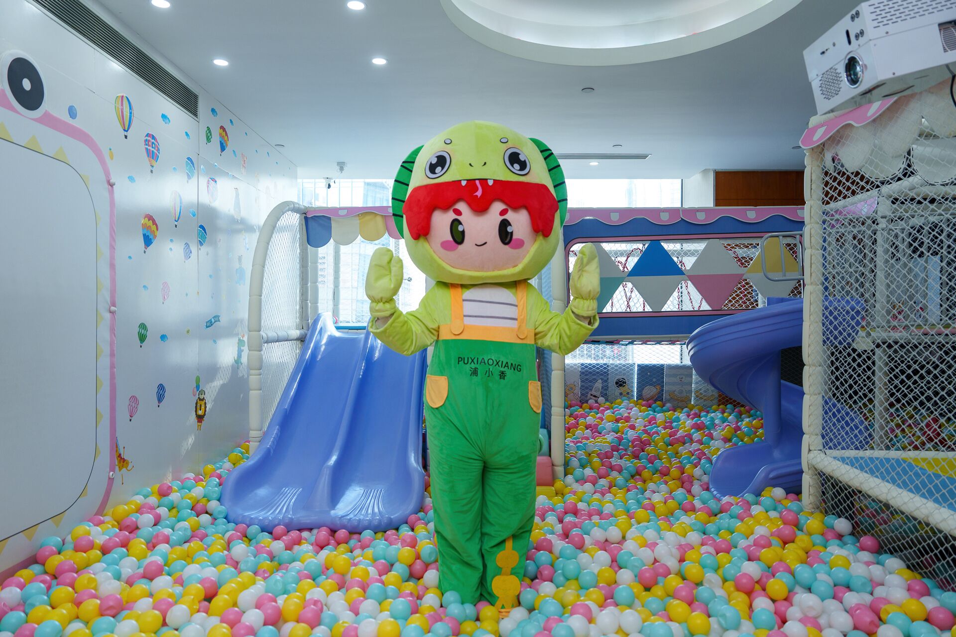 Uma área de recreação com escorregador, piscina de bolinhas e um mascote.