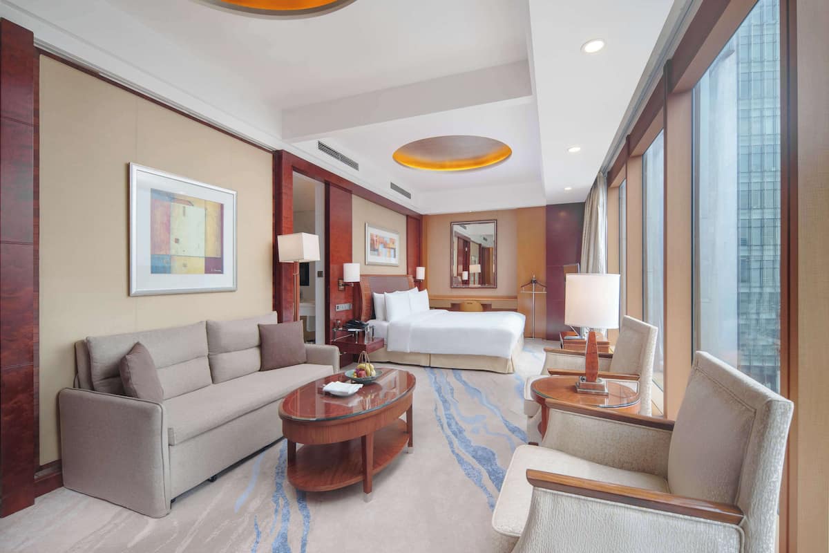 Quarto de hotel com sofá, cama, mesa de centro e uma cadeira.