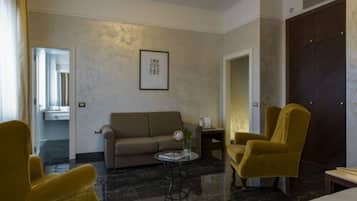 Quarto de hotel com sofá, duas poltronas amarelas, uma mesinha e um quadro na parede.