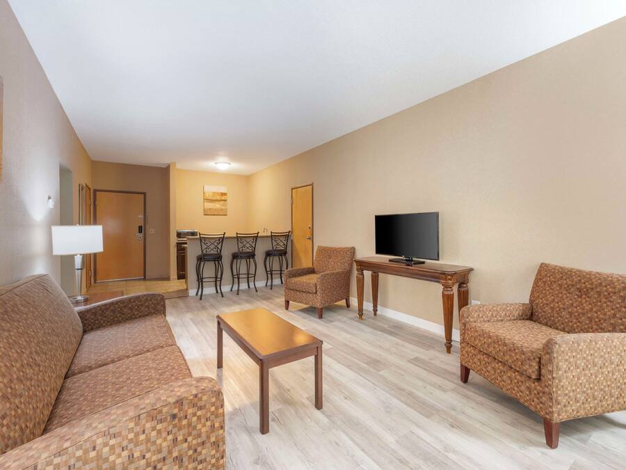 Uma sala de estar com sofá, poltronas, mesa de centro, televisão e uma área de jantar com cadeiras e mesa.